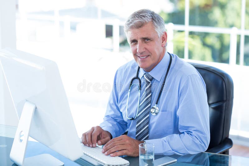Smiling Doctor Working on Computer at His Desk Stock Image - Image of ...