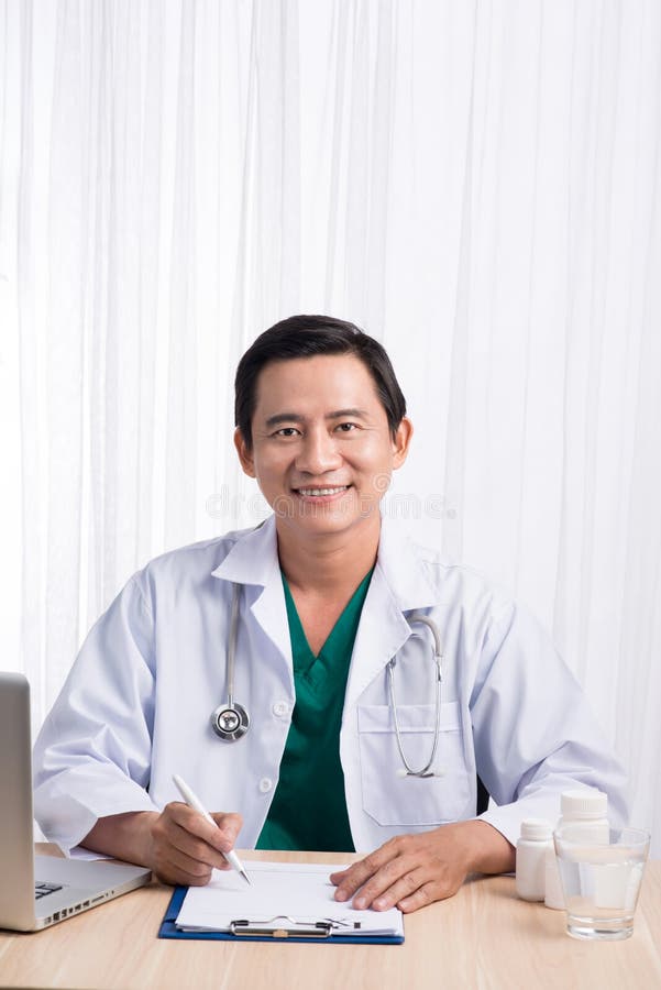 Smiling Doctor Working on Computer at His Desk in Medical Office Stock ...