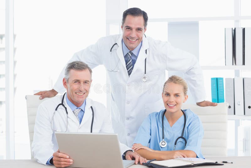 Doctors and Nurse Looking at Laptop and Smiling at Camera Stock Photo ...