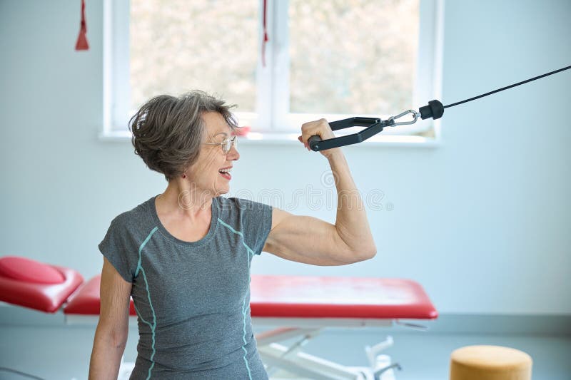 Smiling Elderly Lady is Working Out on a Special Exercise Machine Stock ...
