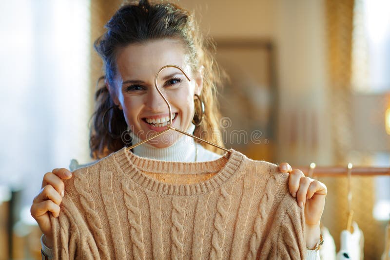 Smiling Elegant Woman Holding Sweaters on Copper Hanger Stock Photo ... Smiling Elegant Woman Holding Sweaters on Copper Hanger Stock Photo ...