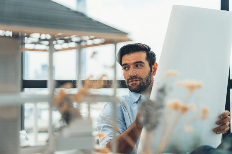 Smiling Engineer Looking Project Plan while Design House Model. Office ...