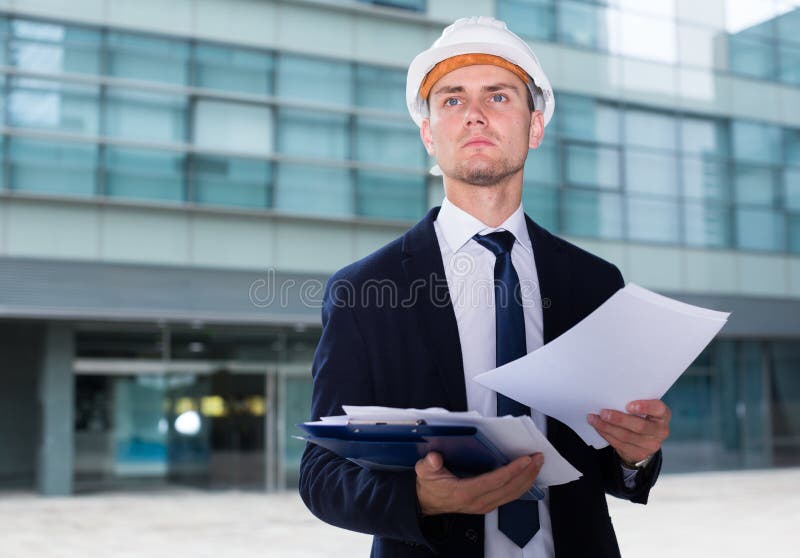 Smiling Engineer in Suit and Hat with Folder is Exploring Documents ...