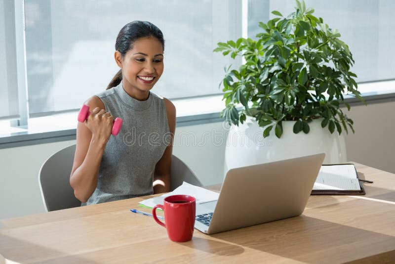 Smiling Executive Exercising with Dumbbells while Working Laptop Stock ...