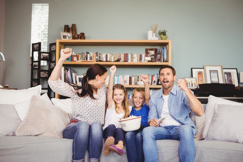 Smiling Family with Arms Raised while Watching Television Stock Image ...