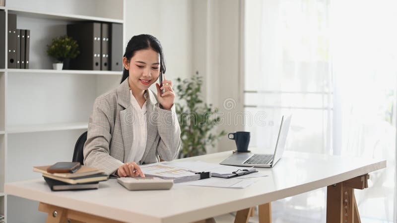 Smiling Female Accountant Talking on Mobile Phone and Checking ...