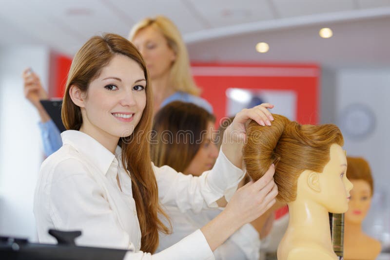 Smiling Female Apprentice Holding Dummy with Wig in Hair Salon Stock ...