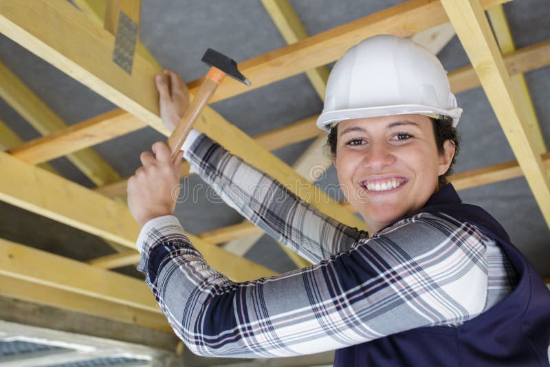 Smiling Female Construction Worker Hammering Nail on Timber Frame Stock ...