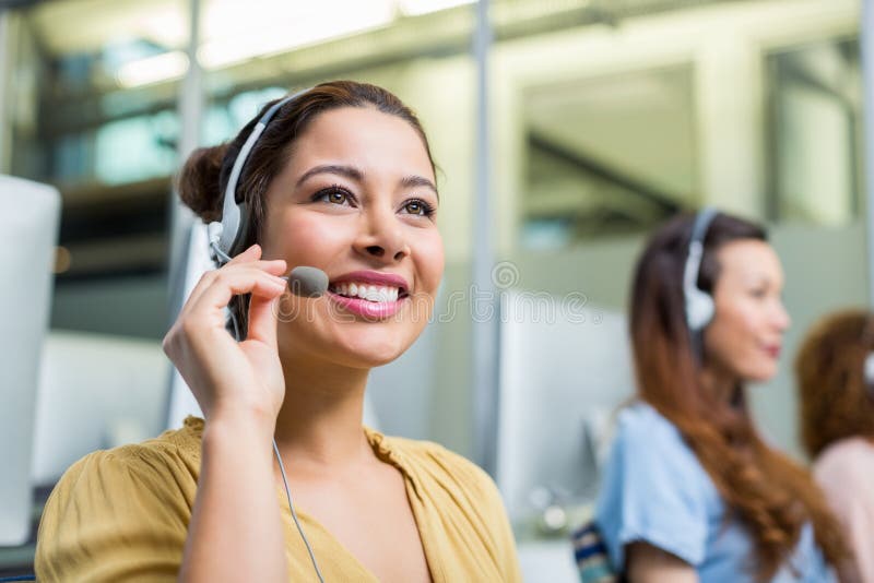 Smiling Female Customer Service Executive Talking on Headset at Desk ... Smiling Female Customer Service Executive Talking on Headset at Desk ...