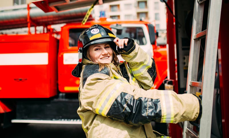 Smiling Female Firefighter in Helmet Looking at Camera Behind at Fire ...
