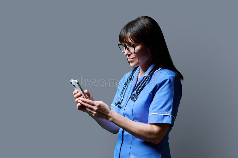Female Nurse Using Smartphone, Profile View on Gray Studio Background ...