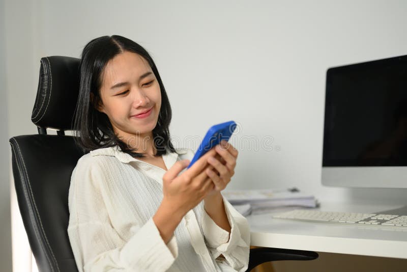 Smiling Female Office Worker Using Mobile Phone at Her Workplace Stock ...