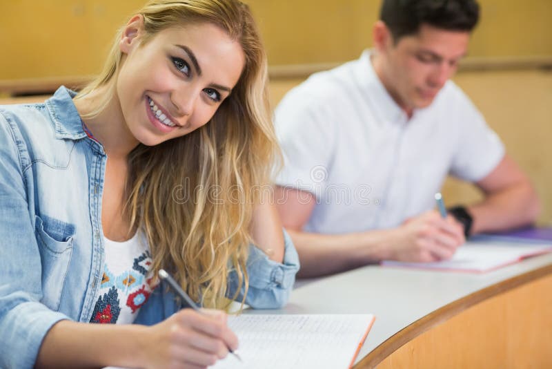 Smiling Female Student Writing during Class Stock Image - Image of ...