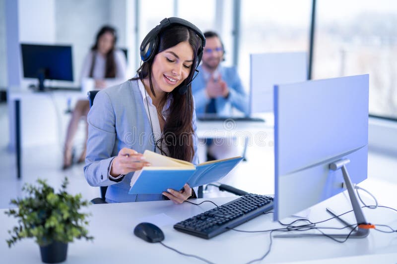 Smiling Female Support Center Agent Checking Schedule in Notebook at ...