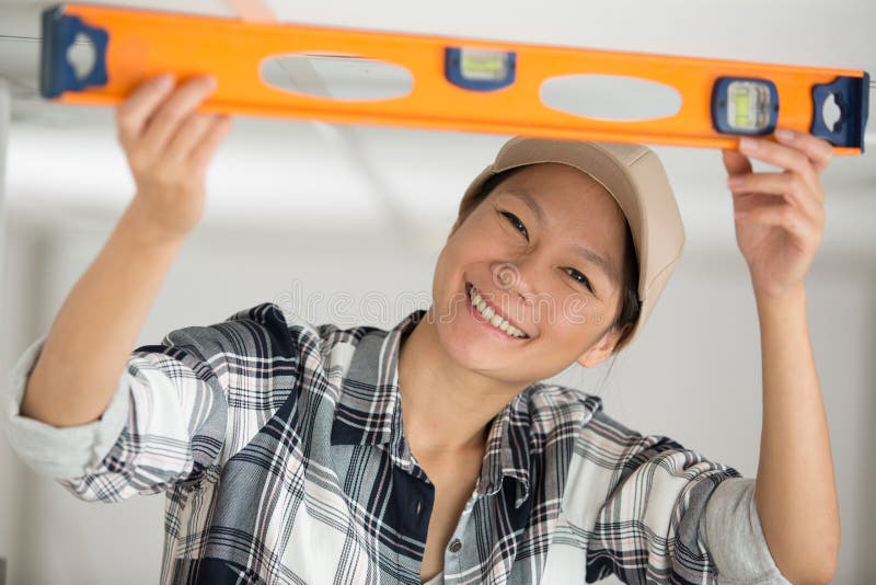 Smiling Female Worker Using Spirit Level Stock Photo - Image of home ...