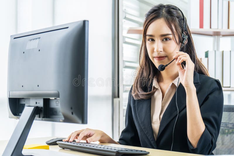 Smiling Friendly Asian Female Call-center Agent with Headset Working on ...