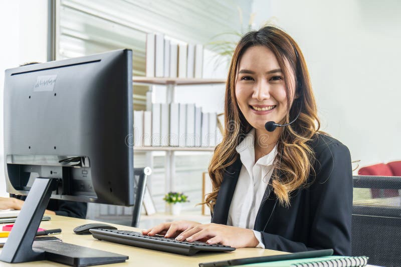 Smiling Friendly Asian Female Call-center Agent with Headset Working on ...