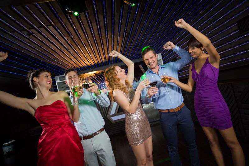 Smiling Friends Holding Glasses of Champagne and Wine while Dancing ...