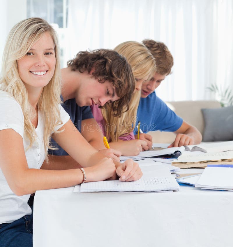 A Smiling Girl Looks at the Camera As Her Friends Study Stock Image ...