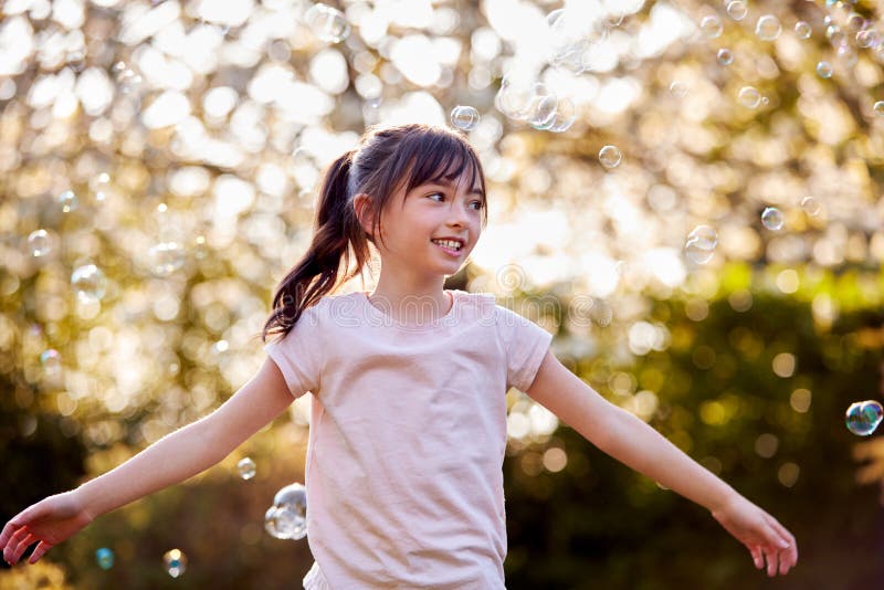 Smiling Girl Outdoors Having Fun Playing with Bubbles in Garden Stock ...