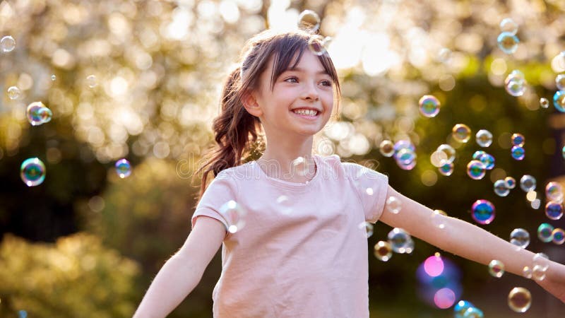 Smiling Girl Outdoors Having Fun Playing with Bubbles in Garden Stock ...