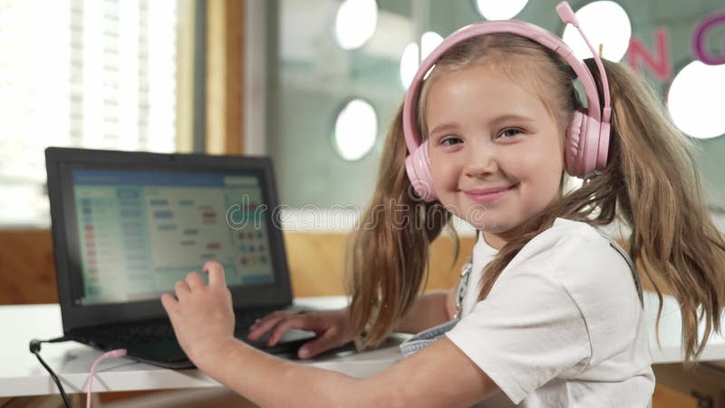 Smiling Girl Looking at Camera while Waving Hand with Laptop Placed ...