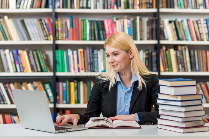 Smiling Girl Sitting at a Desk in the Library Working with Stock Image ...