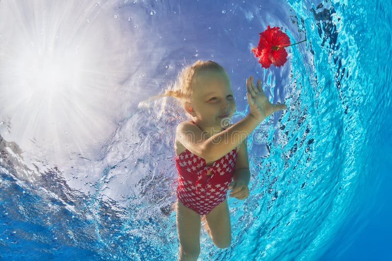 Smiling Girl Swimming Underwater In Pool For Tropical Red Flower Stock