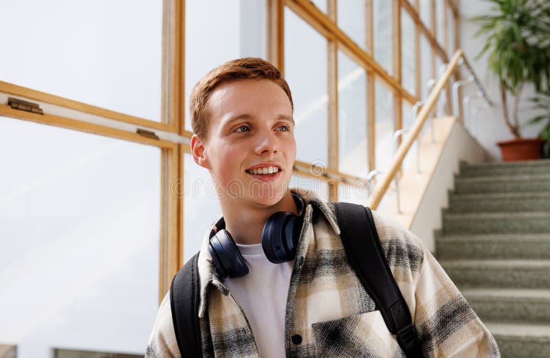 Smiling Guy with Headphones Standing in College and Looking Away Stock ...