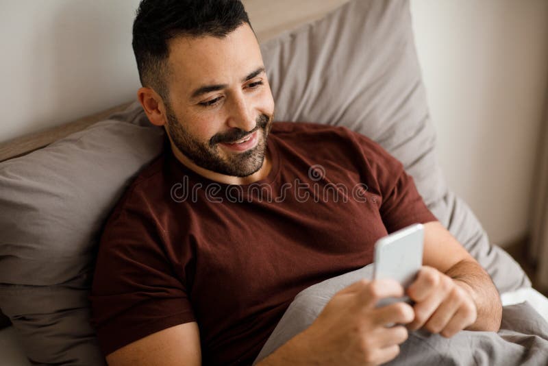 Smiling Guy Using Mobile Phone, Browsing Internet and Sending Messages ...