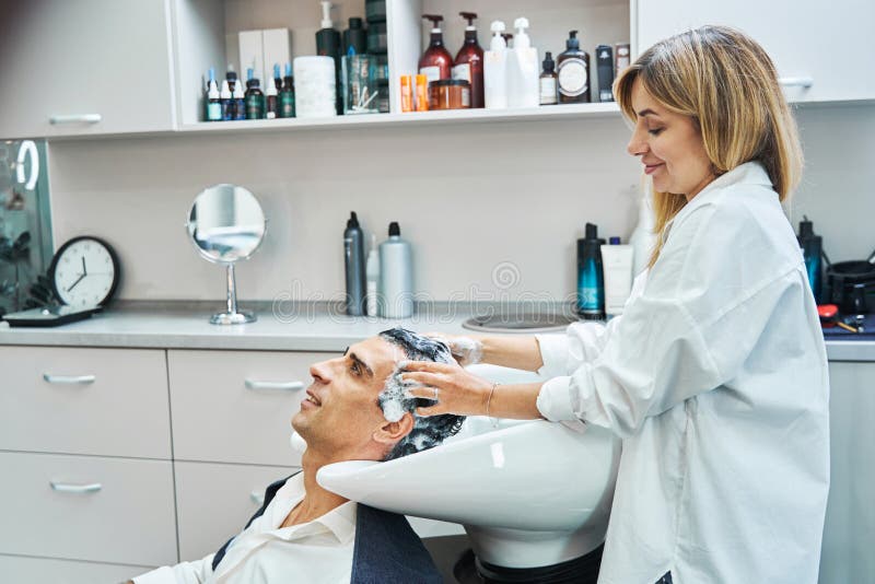 Hairdresser Shampooing His Client Hair At A Sink In A Barber Shop