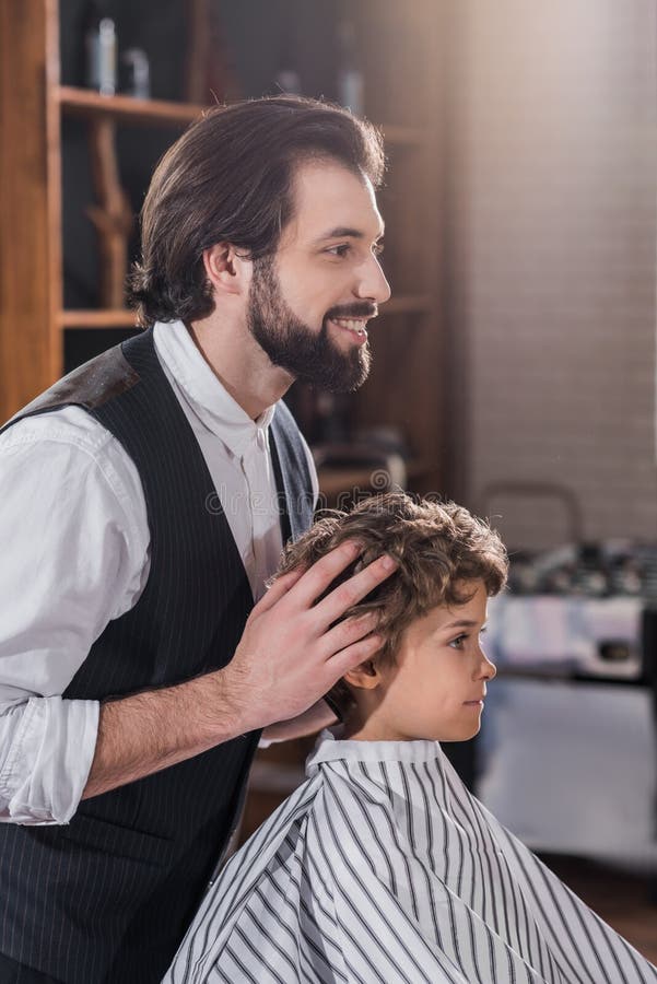 Smiling Handsome Barber Looking at Reflection of Little Kid Sitting in ... Smiling Handsome Barber Looking at Reflection of Little Kid Sitting in ...