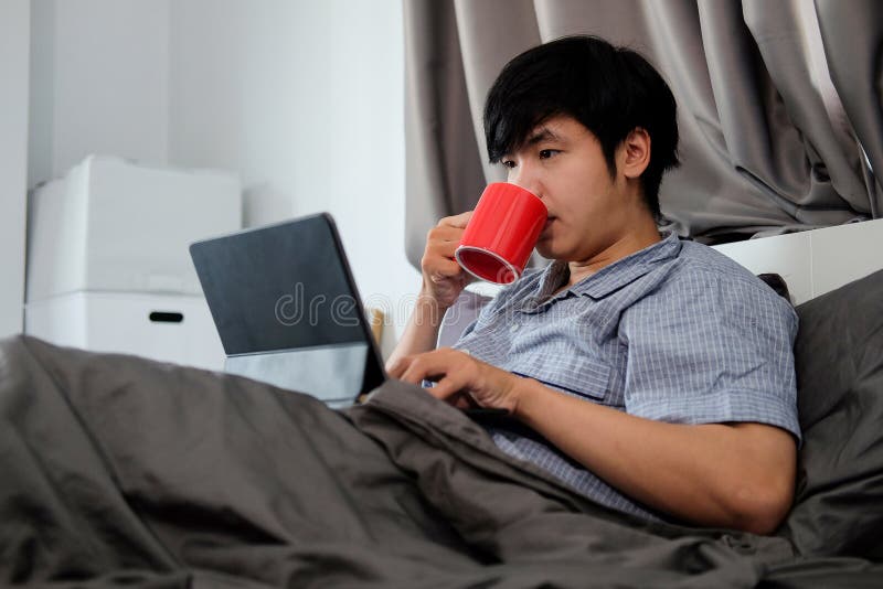 Smiling Handsome Man Drinking Coffee and Using Laptop Computer on Bed ...