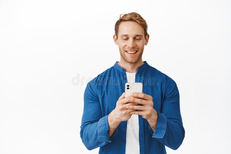 Smiling Handsome Man Looking At His Phone Screen Reading Or Watching
