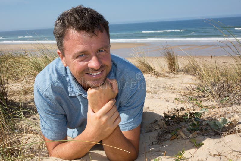 Smiling Handsome Man Relaxing on the Beach Lying on Sand Stock Image ...