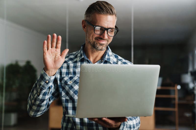 Smiling Handsome Man Waving Hand while Working with Laptop Stock Photo ...