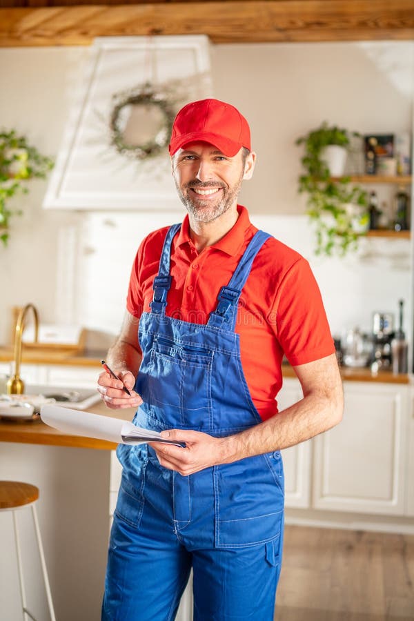 Smiling Handsome Plumber, Repairman Looking at Camera in the Kitchen ...