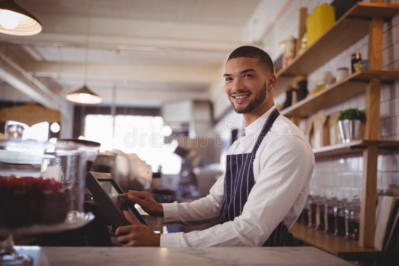 Smiling Handsome Young Waiter Using Computer at Counter Stock Image ...