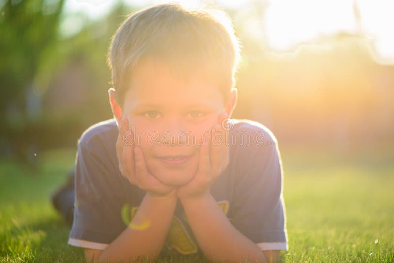 Smiling Little Boy Lying in Green Grass Stock Photo - Image of grass ...