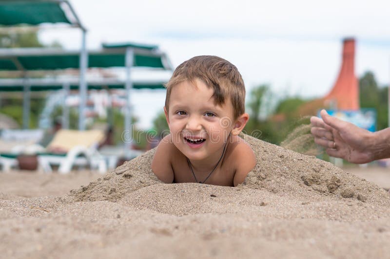 A Little Boy is Playing in the Sand on the Sea, Little Legs and Fingers ...