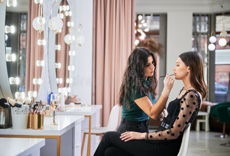 Smiling Makeup Artist Doing Makeup For Woman In Beauty Salon Stock