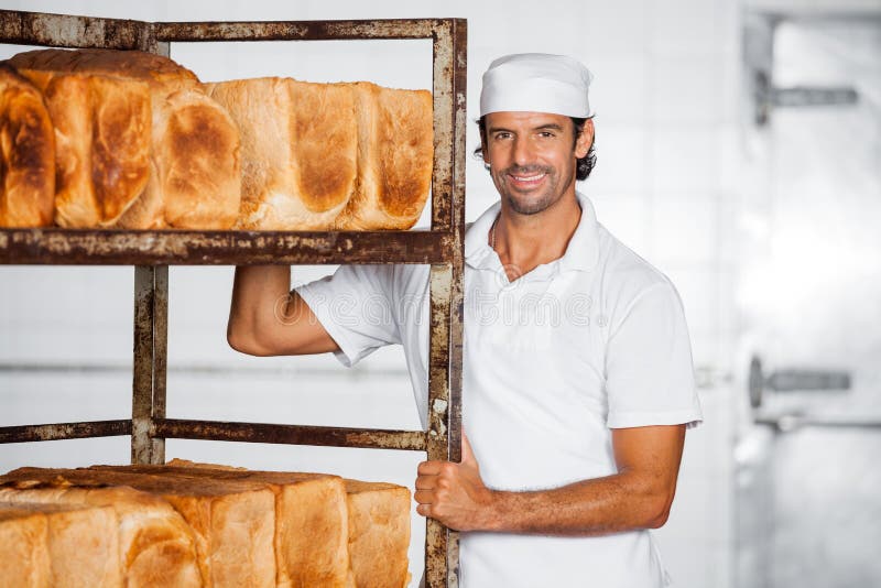Smiling Male Baker Standing by Bread Rack Stock Image - Image of brown ...