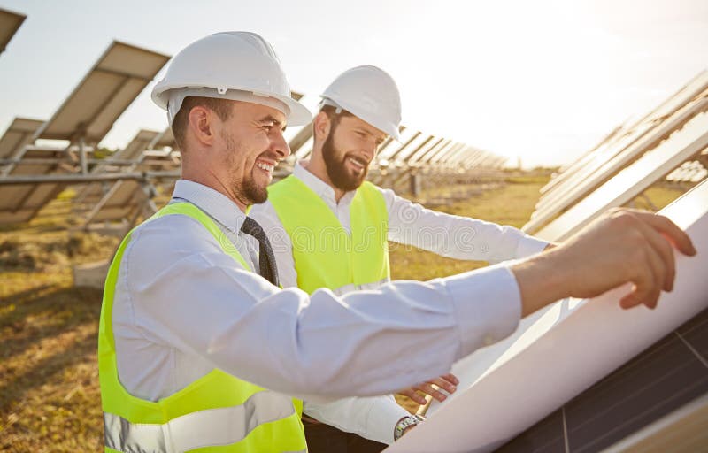 Smiling Male Contractors Checking Solar Panels Draft on Construction ...