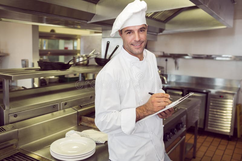 Smiling Male Cook Writing on Clipboard in Kitchen Stock Photo - Image ...