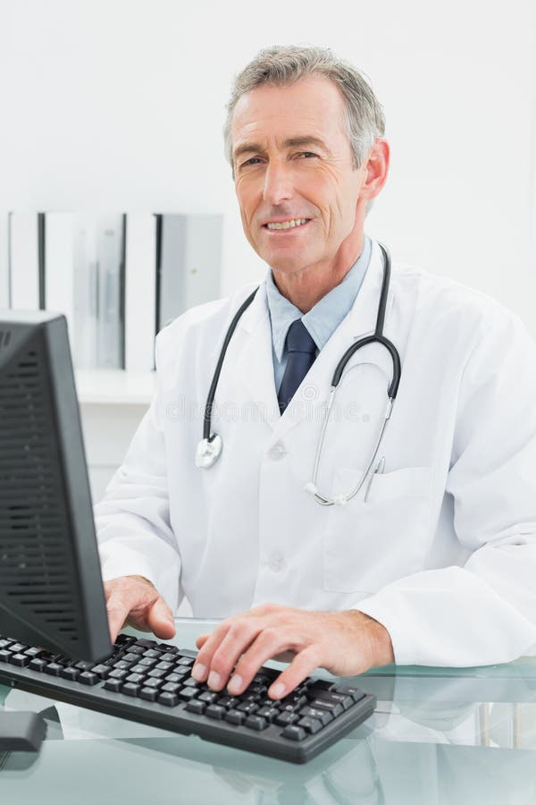 Smiling Male Doctor Using Computer at Office Stock Image - Image of ...