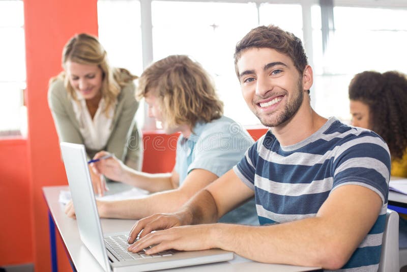 Smiling Male Student Using Laptop in Classroom Stock Photo - Image of ...