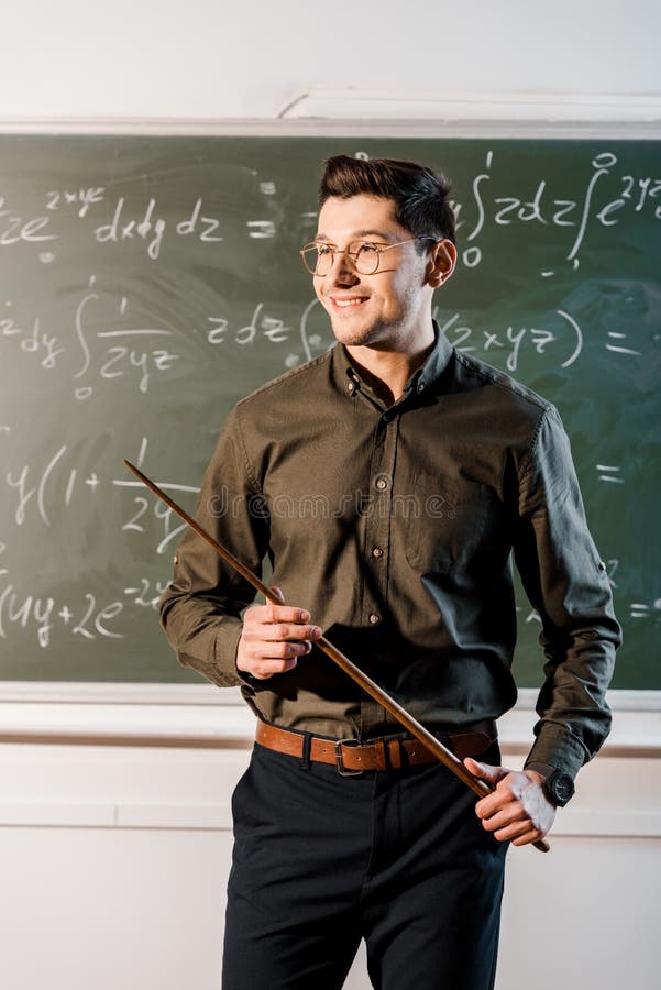 Smiling Male Teacher in Formal Wear Holding Wooden Pointer in Front of ... Smiling Male Teacher in Formal Wear Holding Wooden Pointer in Front of ...
