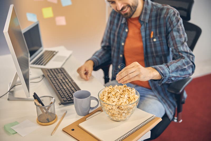 Cheerful Young Man Eating Popcorn at Work Stock Photo - Image of ...