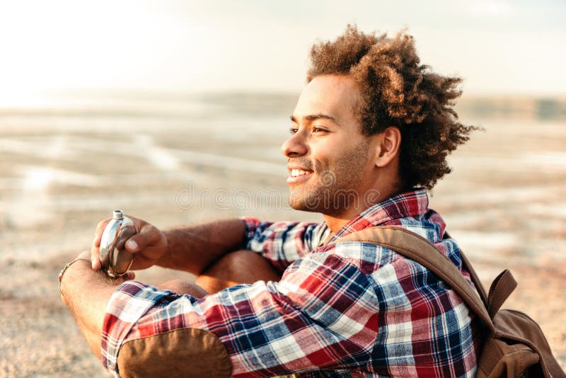 Smiling Man with Backpack Drinking from Hip Flask on Beach Stock Photo ...