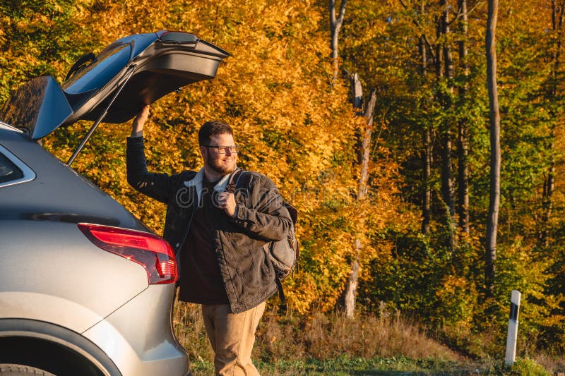 A Smiling Man with a Backpack on His Back Closes the Trunk of the Car ...